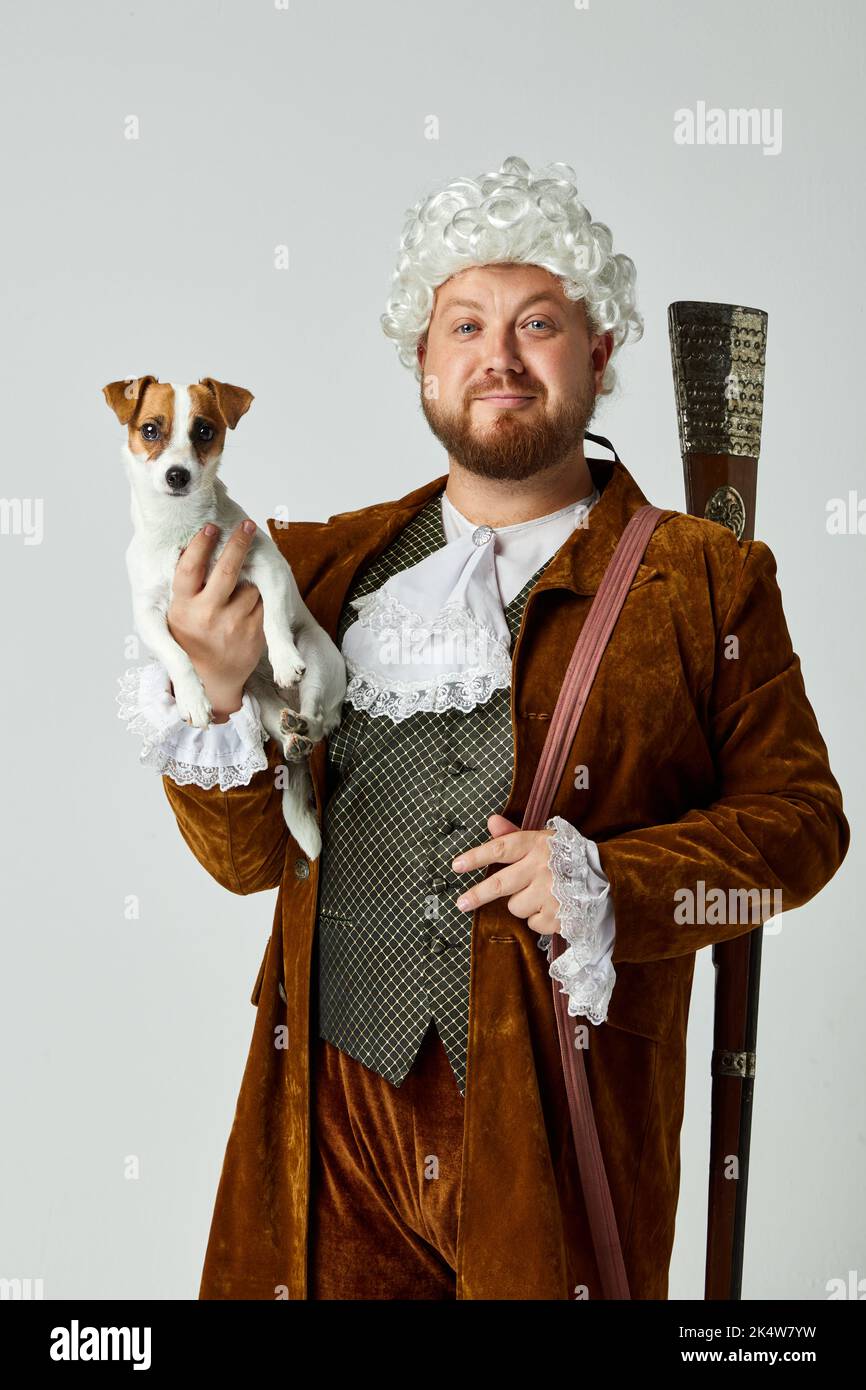 Retro hunter with small dog. Young man in image of medieval person in ...