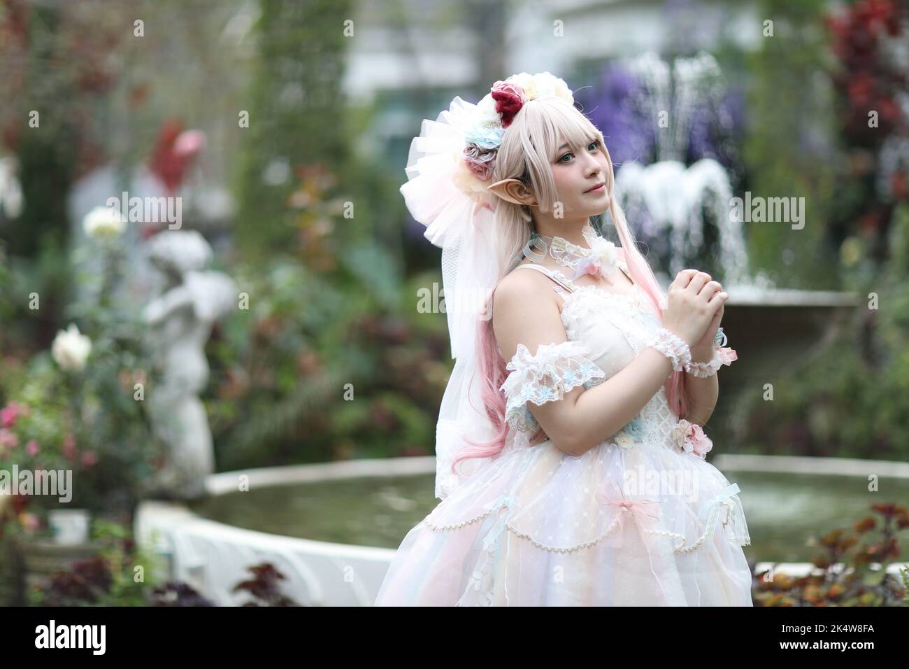 Beautiful young woman with white lolita dress with flowers garden ...