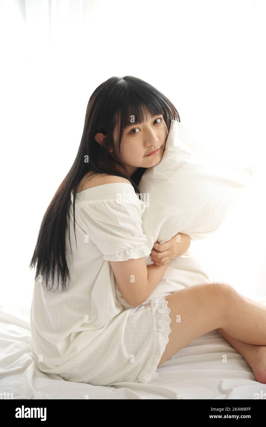 Beautiful young Asian sitting with pillow on bed relaxing in the ...