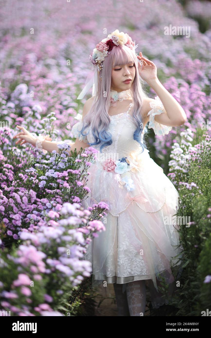 Beautiful young woman with white lolita dress with flowers garden ...
