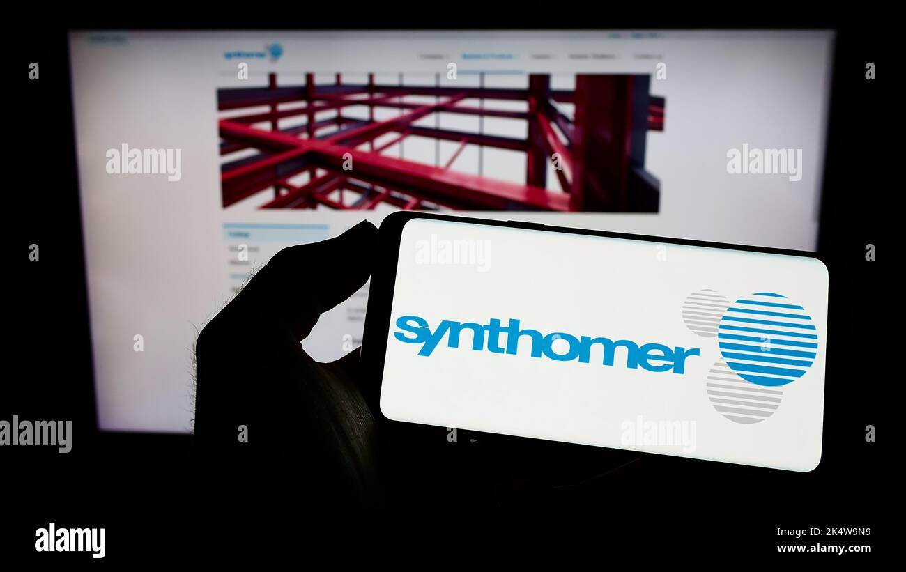 Person holding cellphone with logo of British chemicals company Synthomer plc on screen in front ...