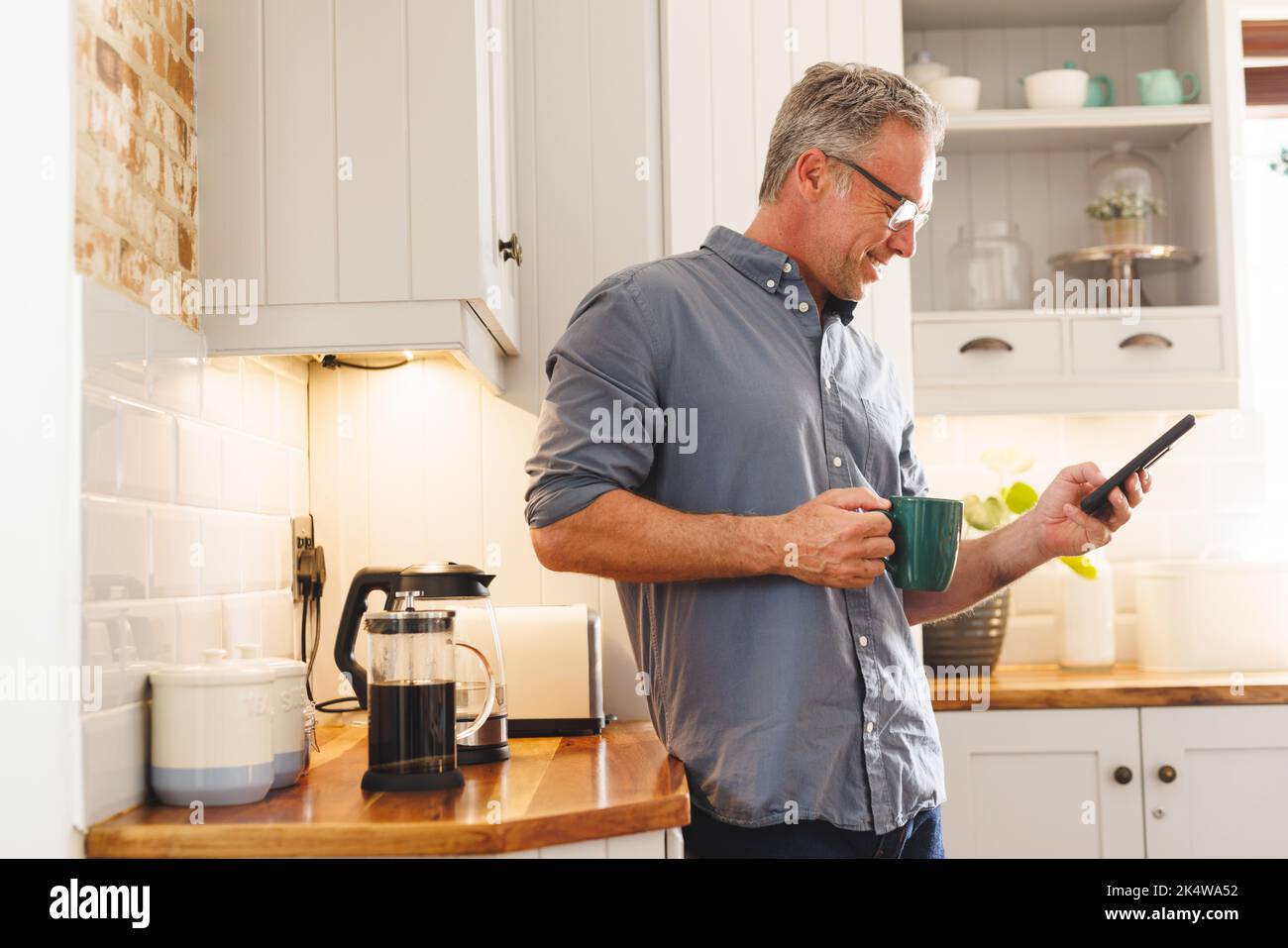Happy caucasian man standing in kitchen and using smartphone Stock ...