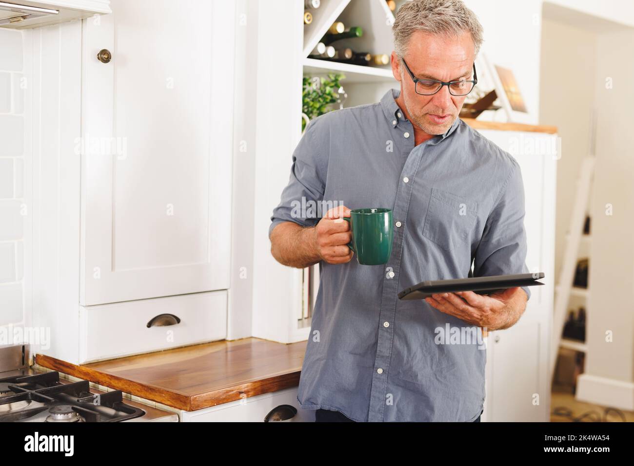Happy caucasian man standing in kitchen and using tablet Stock Photo ...