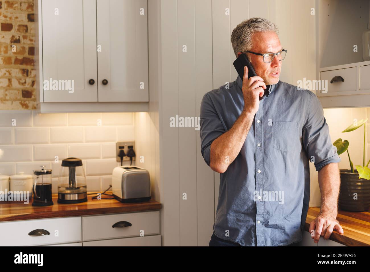 Happy caucasian man standing in kitchen and talking on smartphone Stock ...