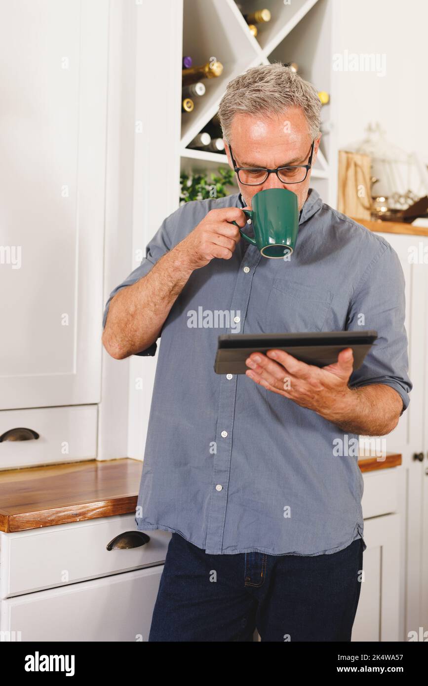 Happy caucasian man standing in kitchen and using tablet Stock Photo ...