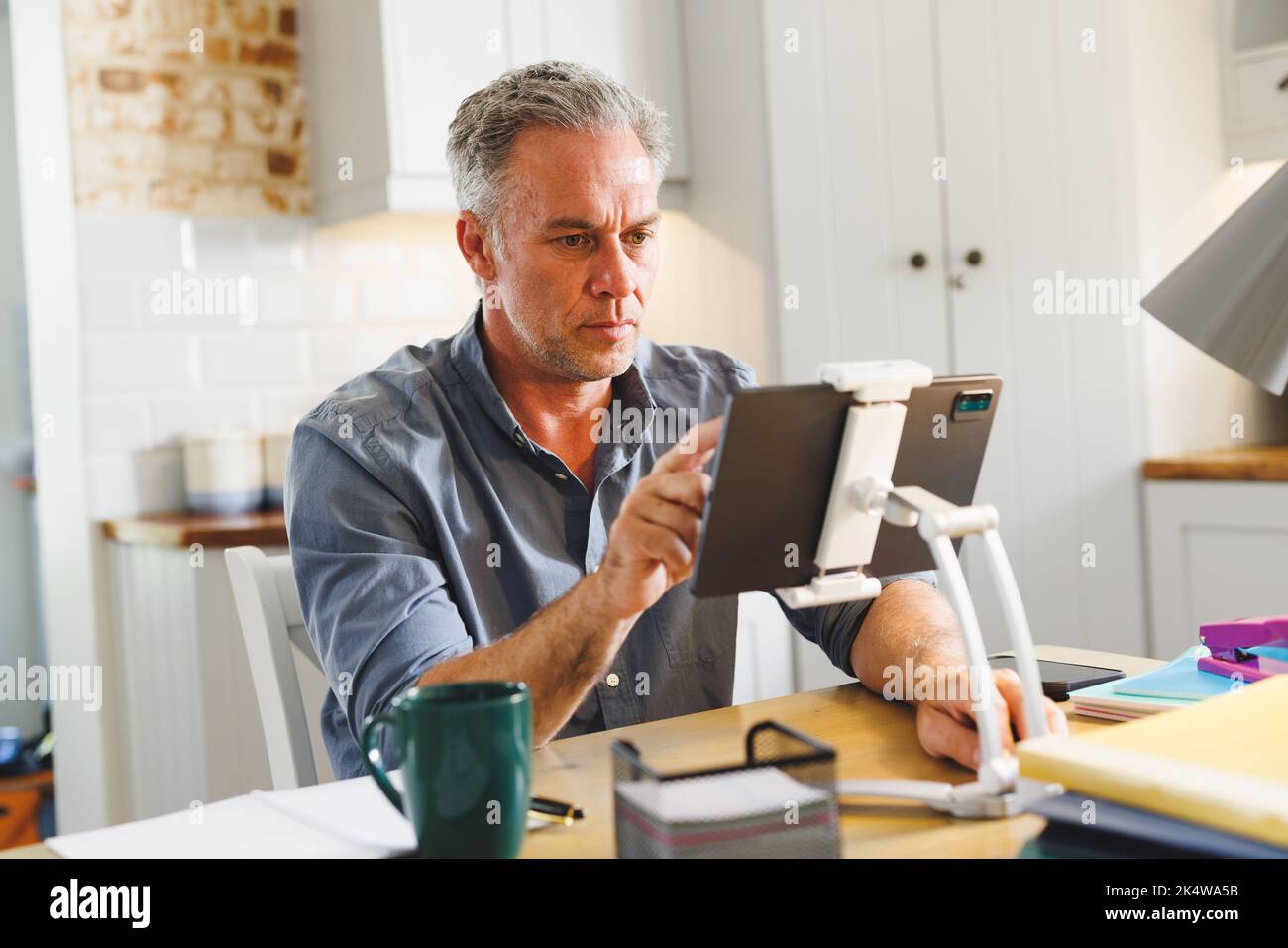 Happy caucasian man sitting at table in kitchen and using tablet Stock ...