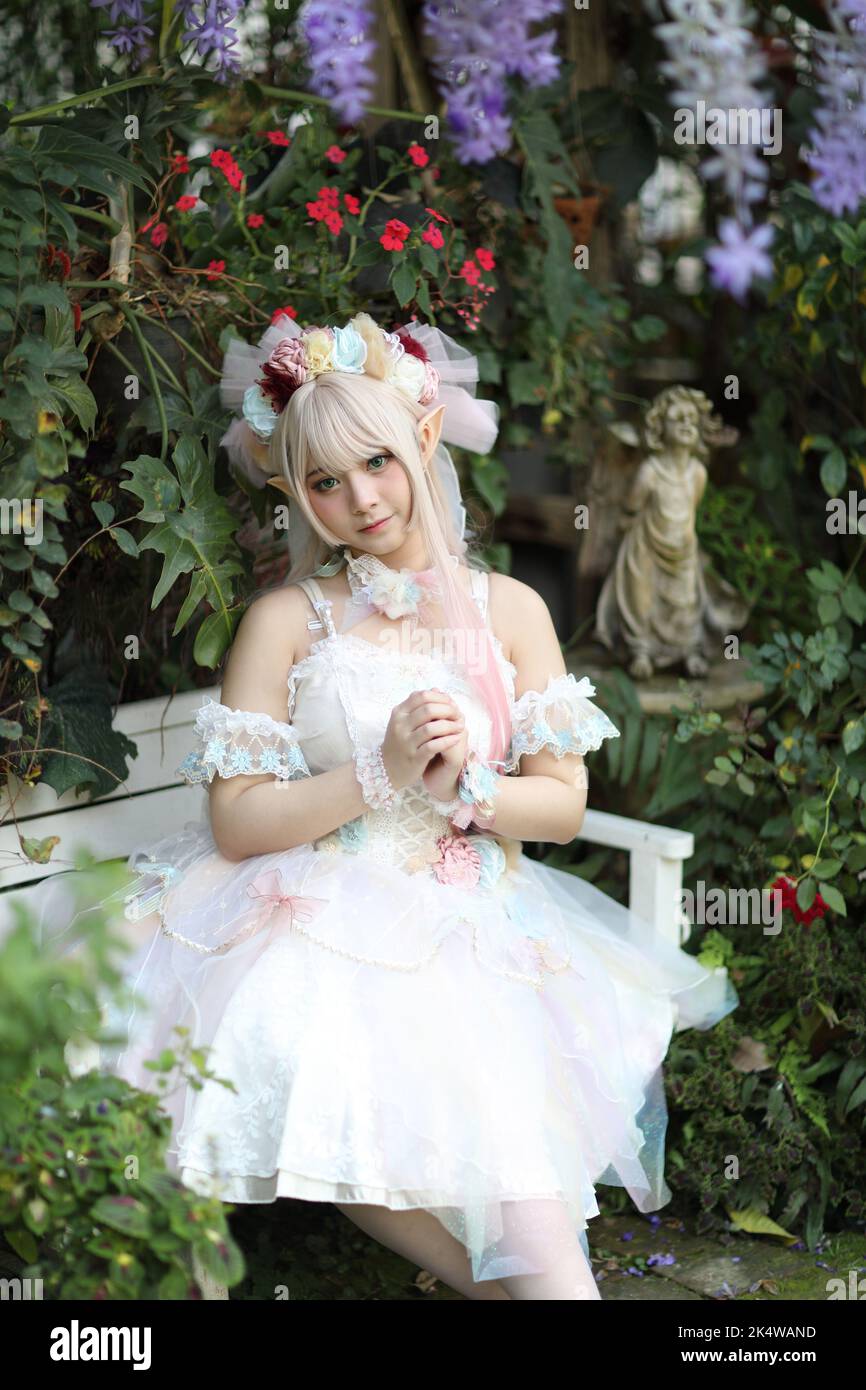 Beautiful young woman with white lolita dress with flowers garden ...