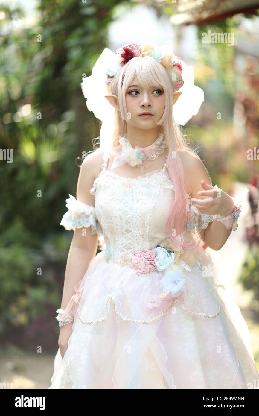 Beautiful young woman with white lolita dress with flowers garden ...