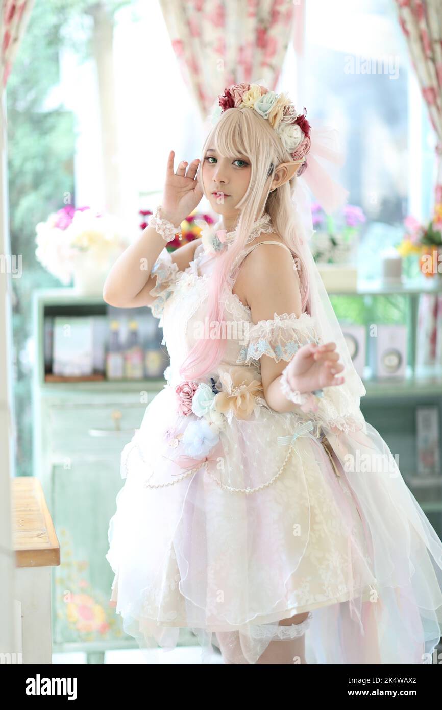 Beautiful young woman with white lolita dress with flowers garden ...