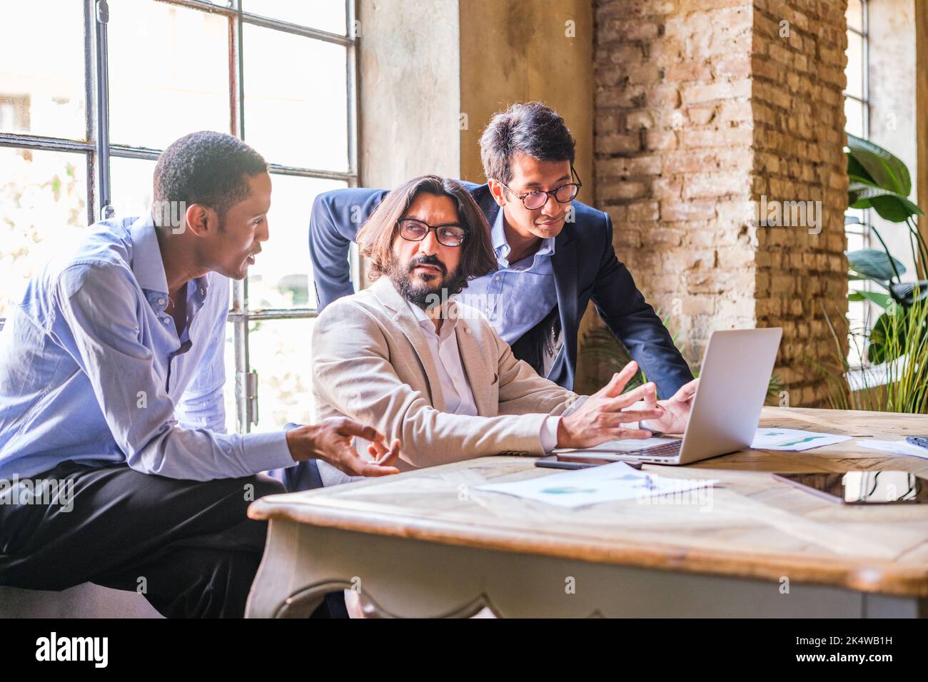 Group of co-workers solving together in front of the computer and ...