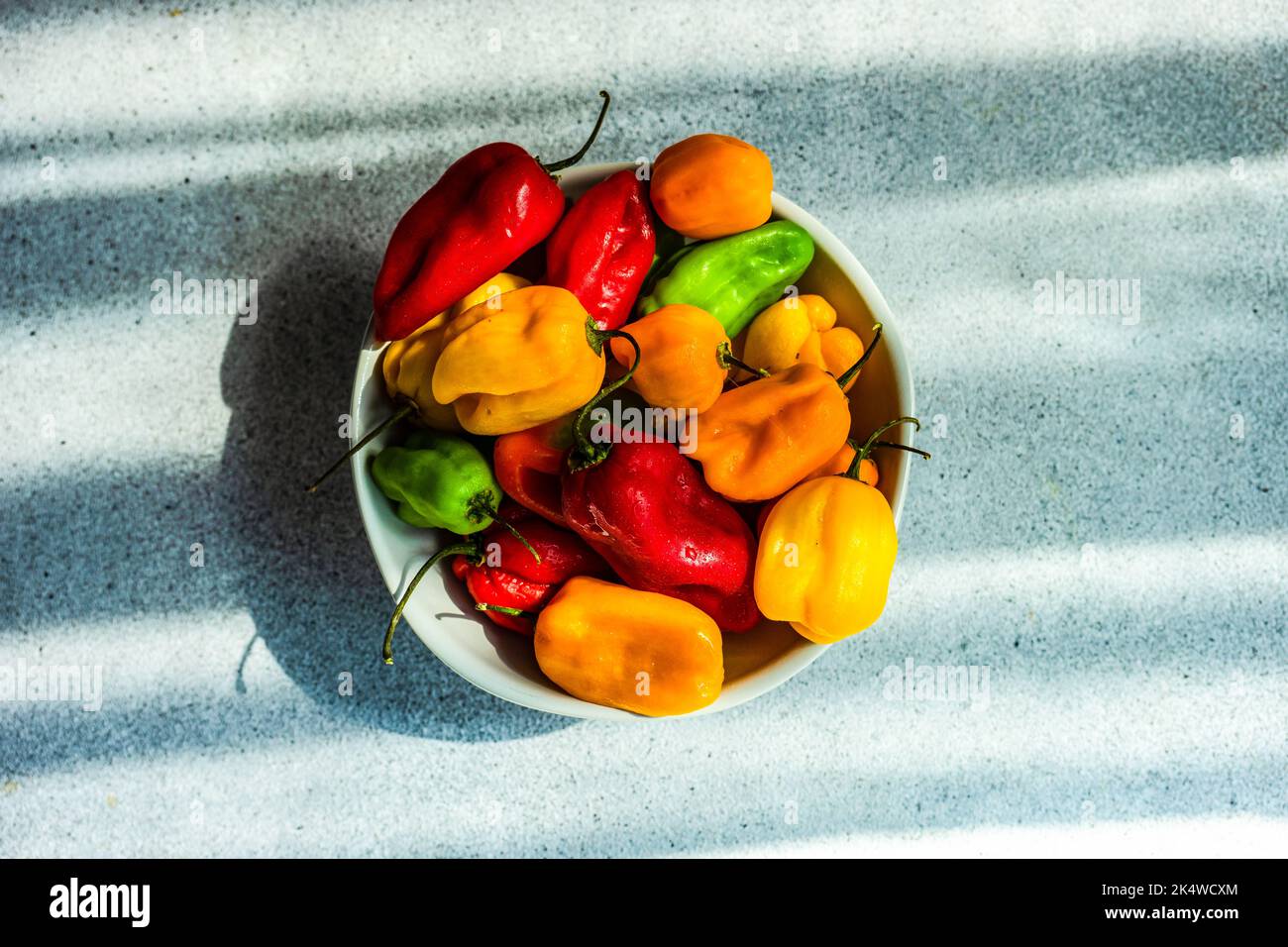 Overhead view of a bowl of assorted red, yellow and green chilli ...