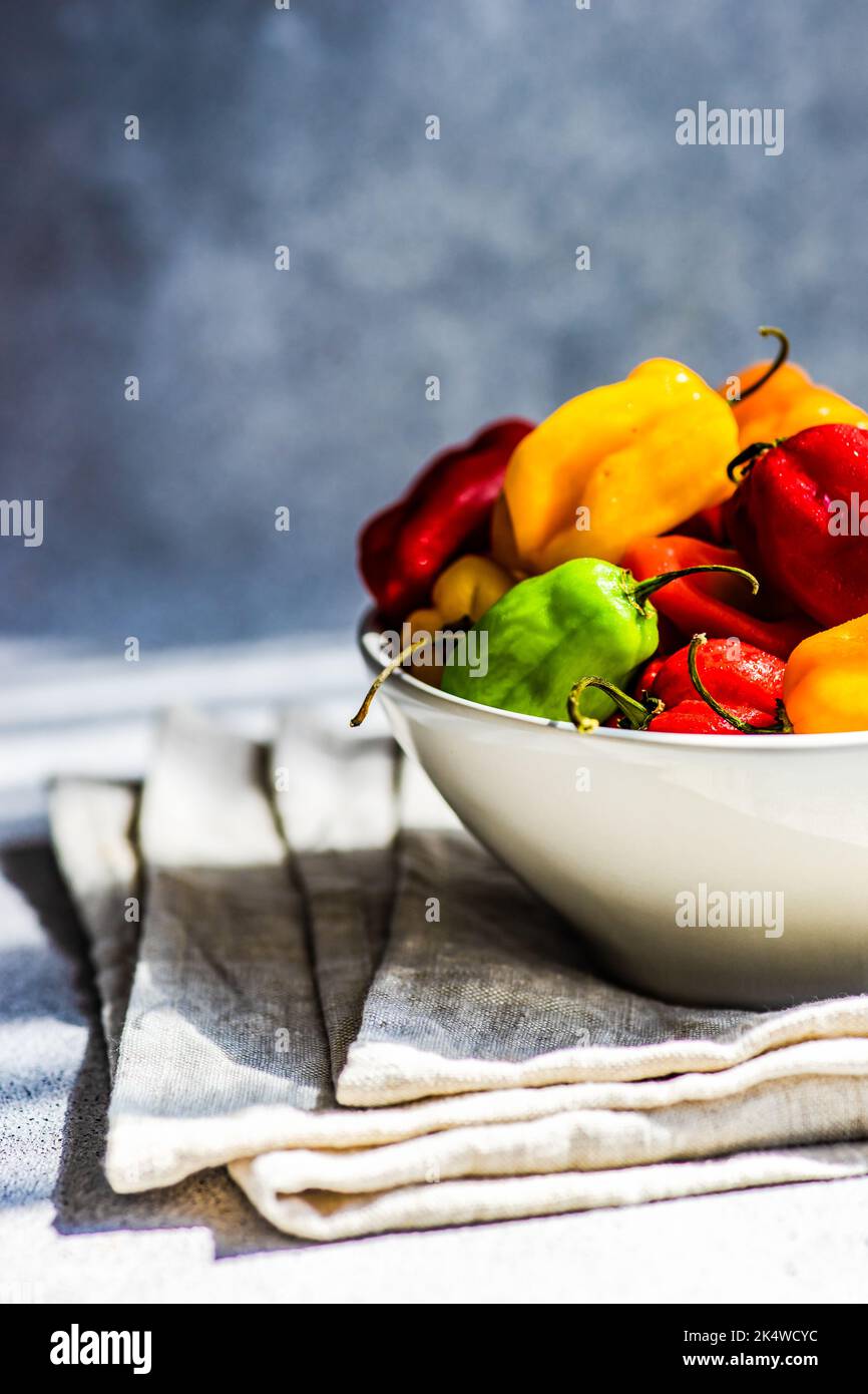Close-up of a bowl of assorted red, yellow and green chilli peppers ...