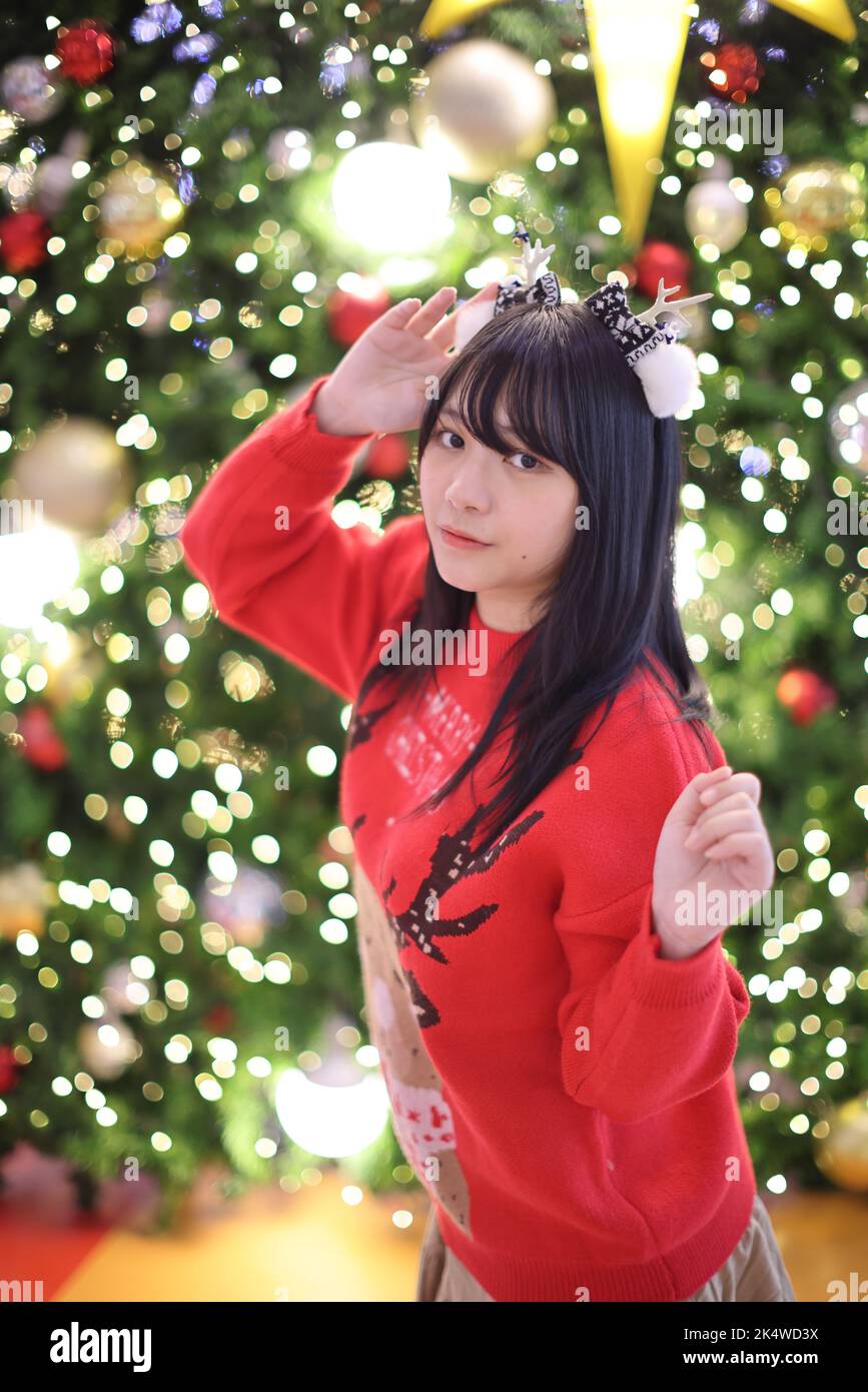 Beautiful Asian young woman with a red sweater with Christmas tree ...