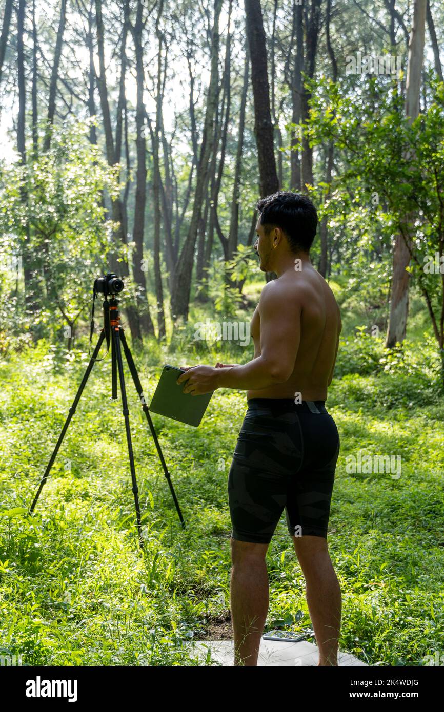 Mature middle-aged athlete man standing in stand position in sporty clothes on fitness mat ...