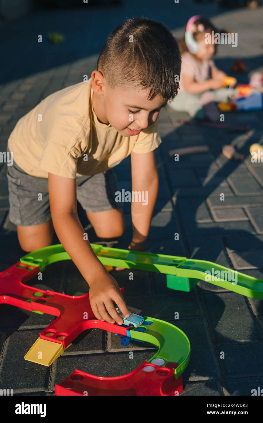 Cute caucasian boy playing with toy railway at the playground in the ...
