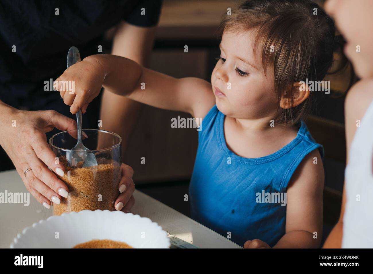 Mother and daughter adding ingredients in bowl, make dough, standing on ...