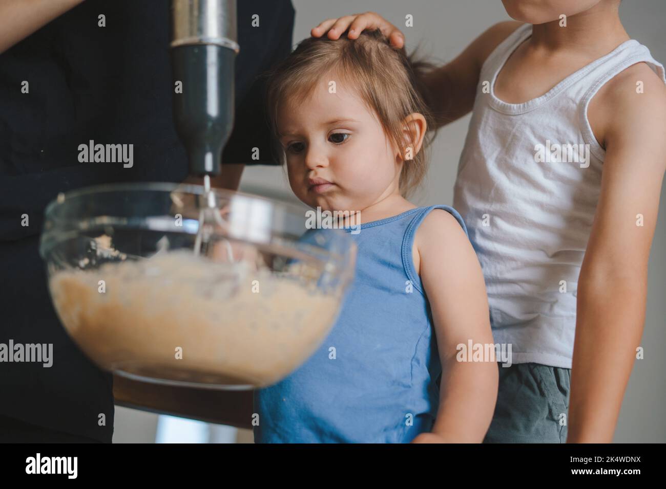 Family cooking pastries together in kitchen, mixing ingredients: eggs ...