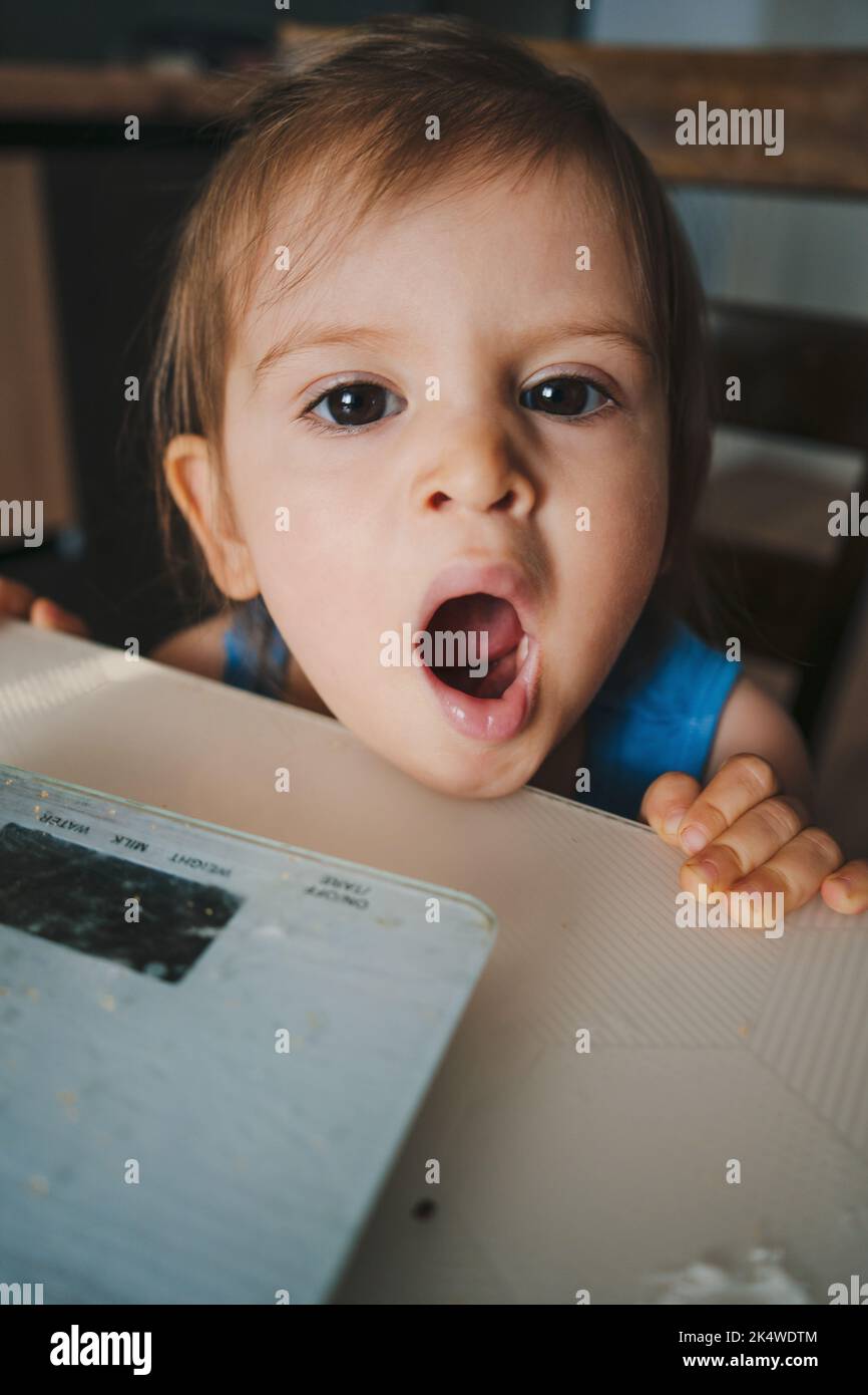 The baby girl is bored to cook in the kitchen with her family. People ...
