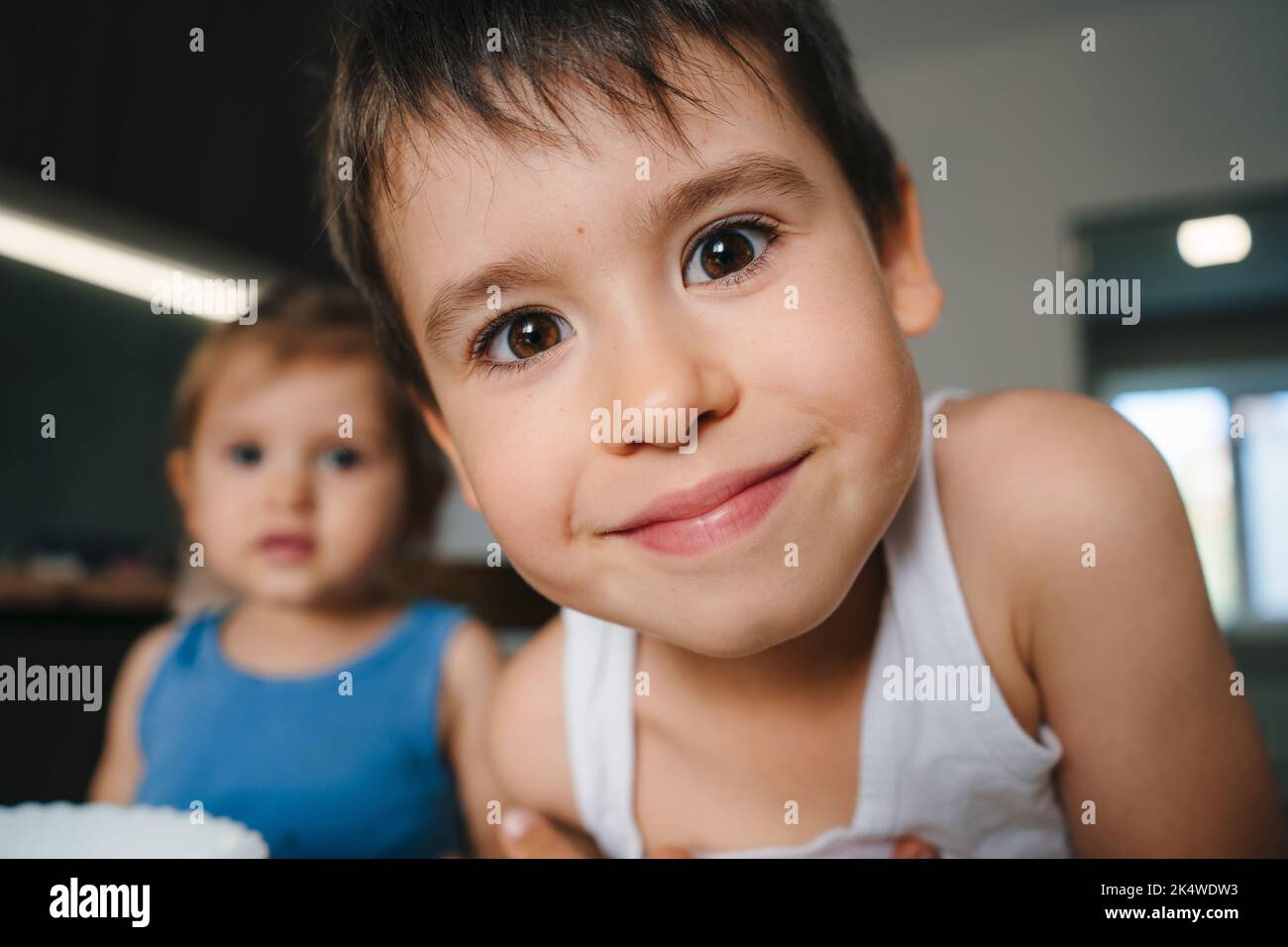 Boy making funny faces at the camera while cooking in the kitchen with ...