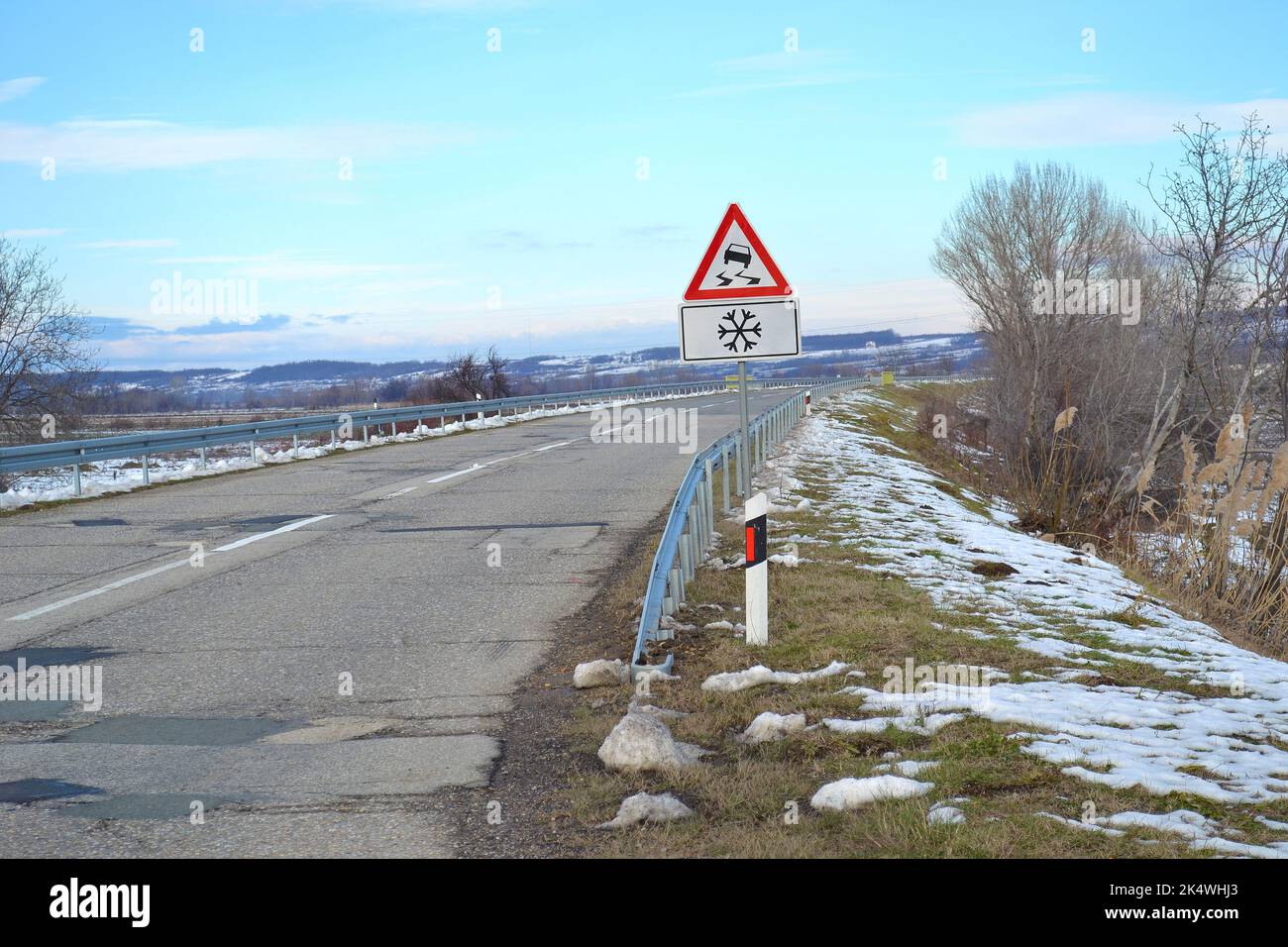 Road sign that warns drivers that the road is slippery in case of snow ...