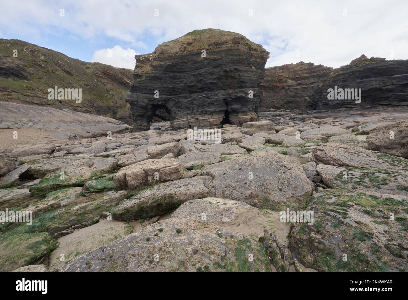 Geological arch with barnacle encrusted rocks in foreground at ...
