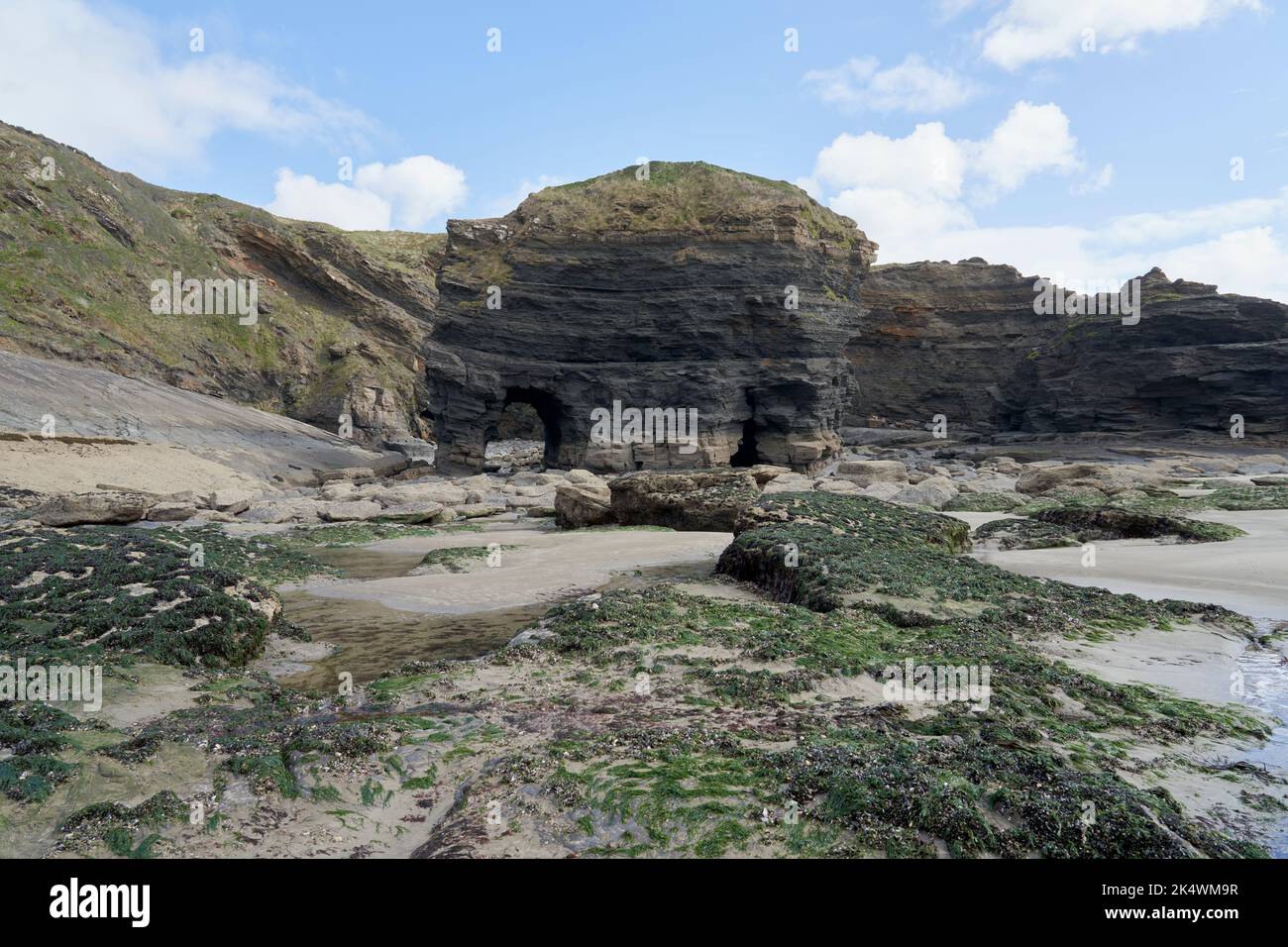 Geological arch with barnacle encrusted rocks in foreground at ...