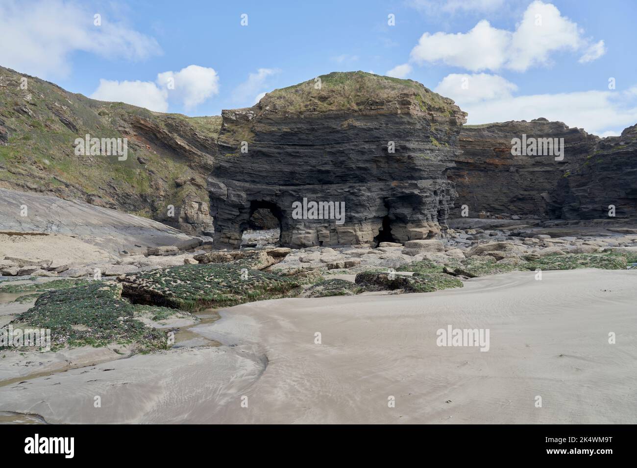 Geological arch with barnacle encrusted rocks in foreground at ...