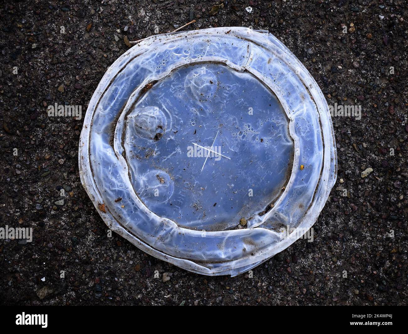 Detail of worn plastic cup lid as trash on sidewalk Stock Photo - Alamy