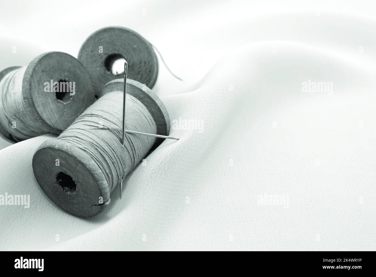 Retro needle and thread lie on the fabric. Tools for a tailor or ...