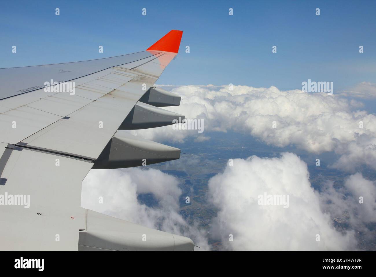 Aircraft window passenger view with a wing above clouds. Airplane above ...