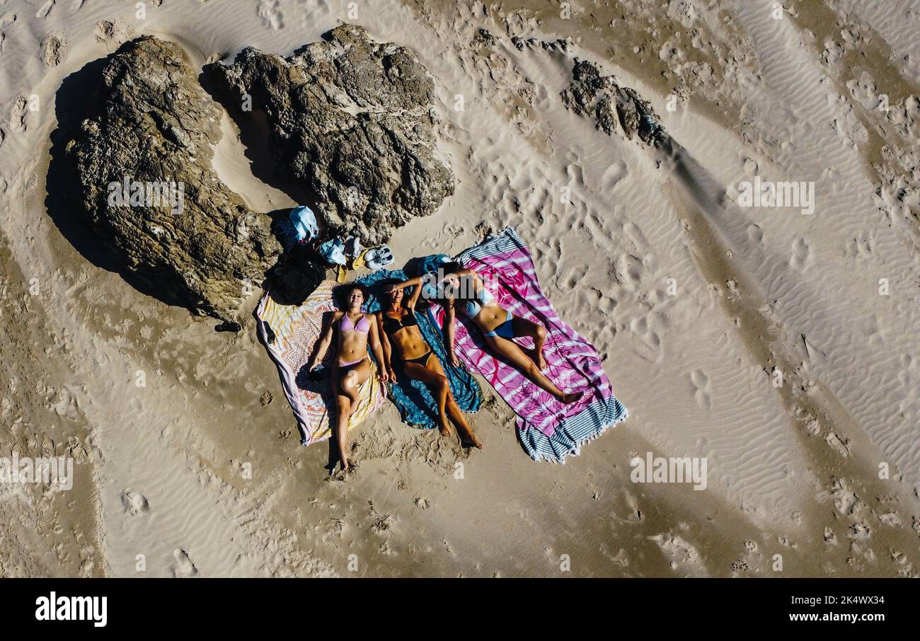 bird's eye view of three women lying on the sand on the beach Stock ...