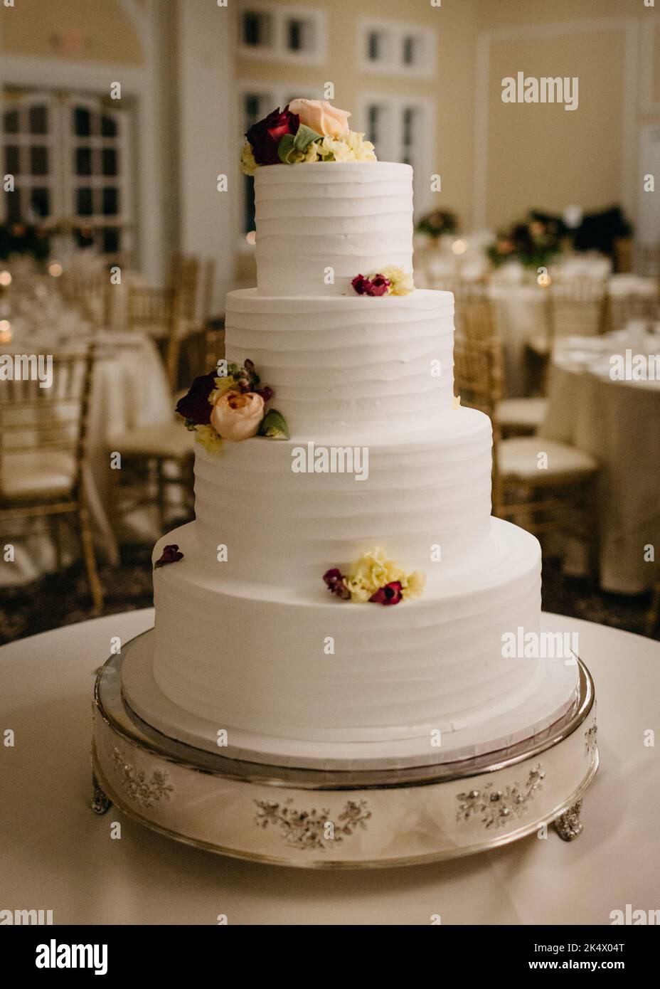 Simple four layer white wedding cake on a cake stand at a reception ...