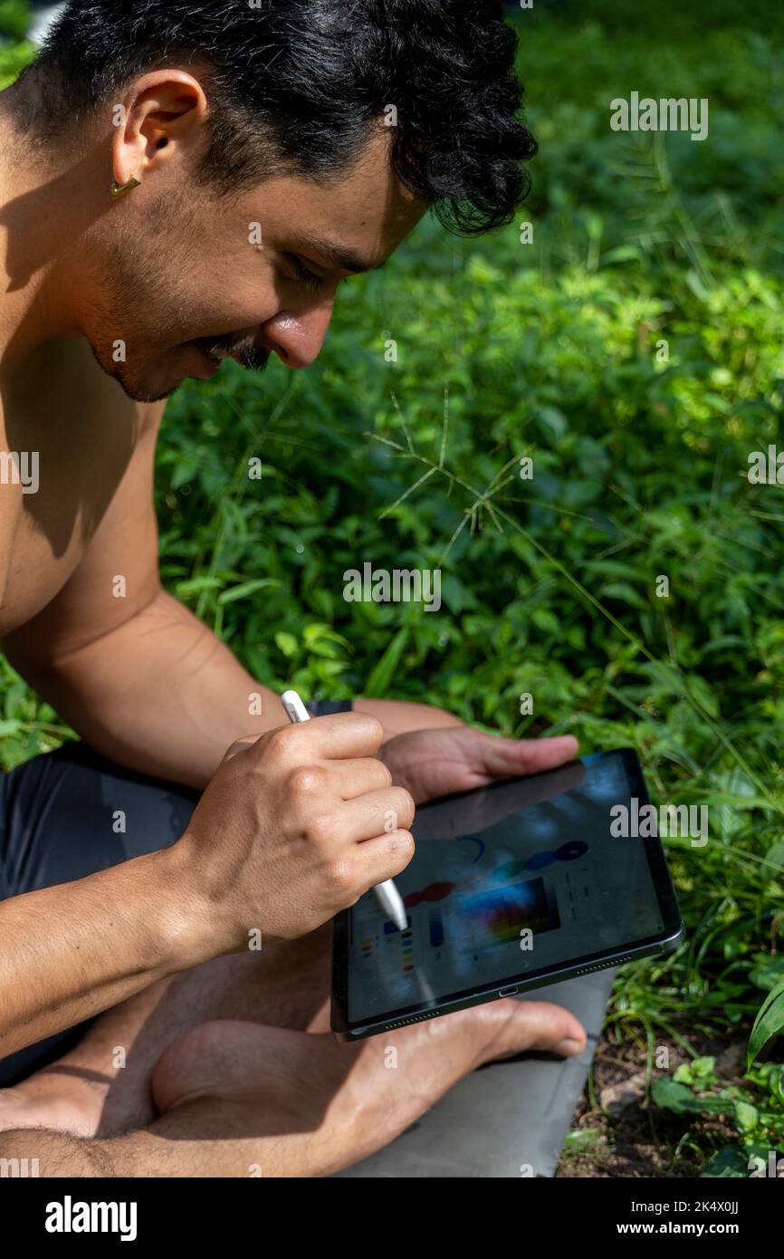 Active handsome male yogi drawing tablet strolling forest before or ...