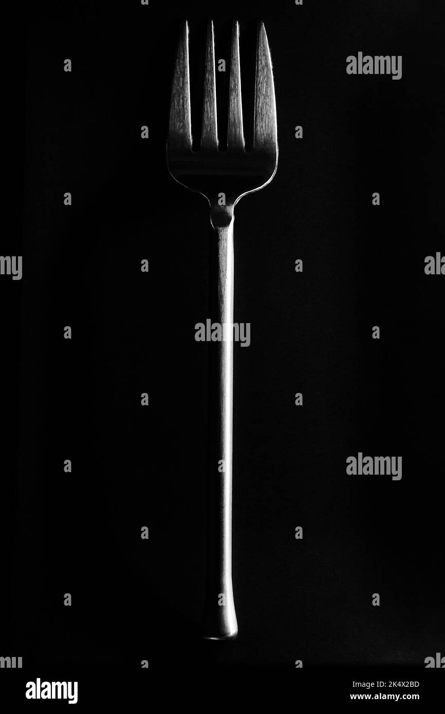 A vertical shot of the fork against a black background Stock Photo - Alamy