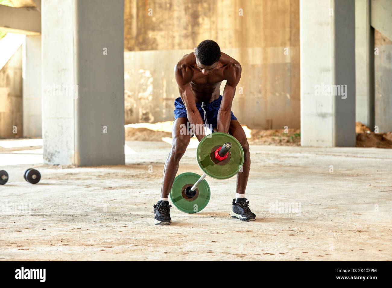 Athletic black young man lifting a heavy-weight barbell in outdoor gym ...