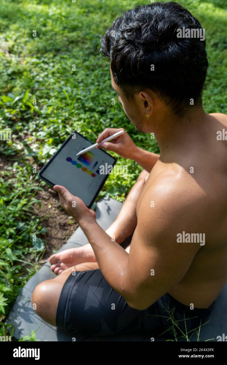 young man explaining drawing on his tablet, while teaching chakra, yoga ...