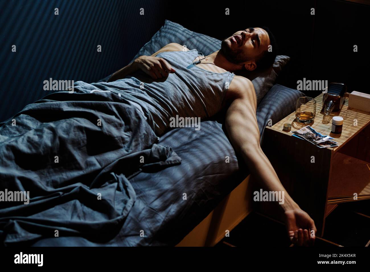 Young stressed man trying to get asleep while lying on bed by night ...