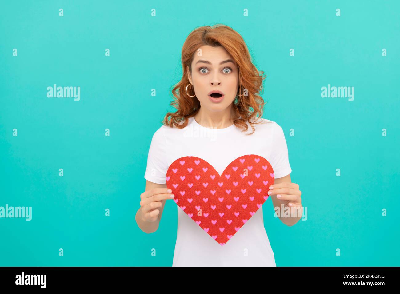 shocked redhead woman hold red heart on blue background Stock Photo - Alamy