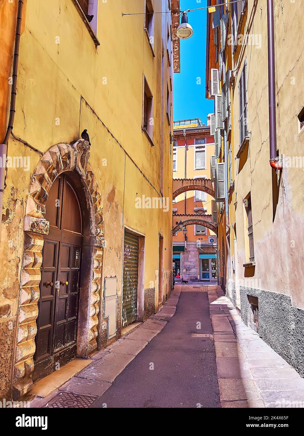 Via Calzavellia street with narrow pedestrian alley and tall colored ...