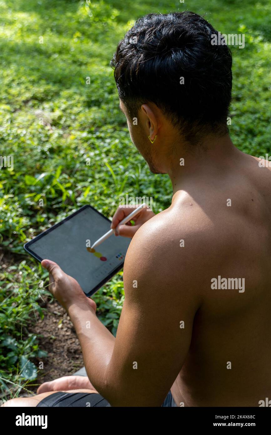 young man explaining drawing on his tablet, while teaching chakra, yoga ...