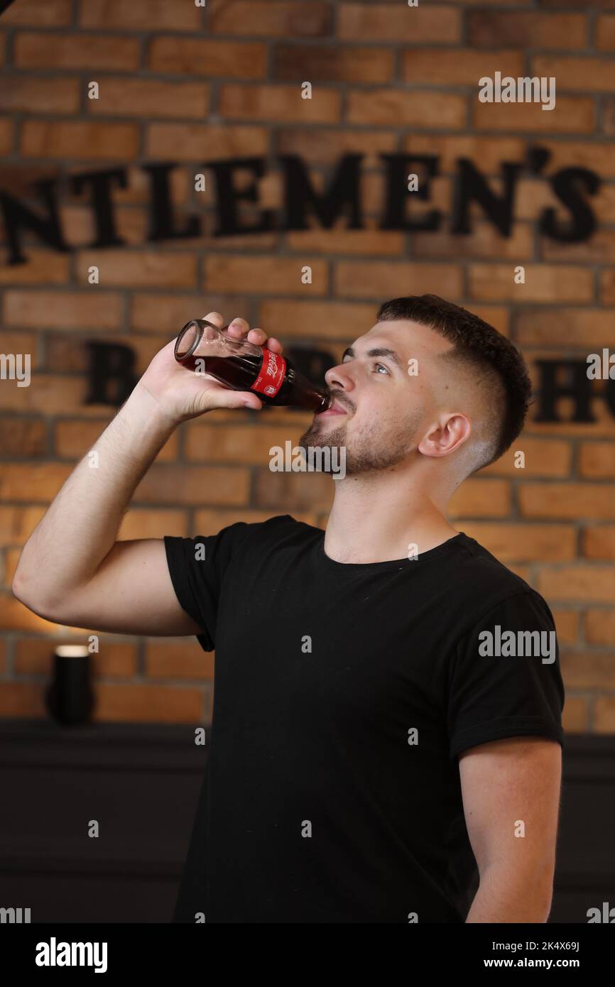 RIVNE, UKRAINE JUNE 26 2020: young bearded man drinking coca cola from ...
