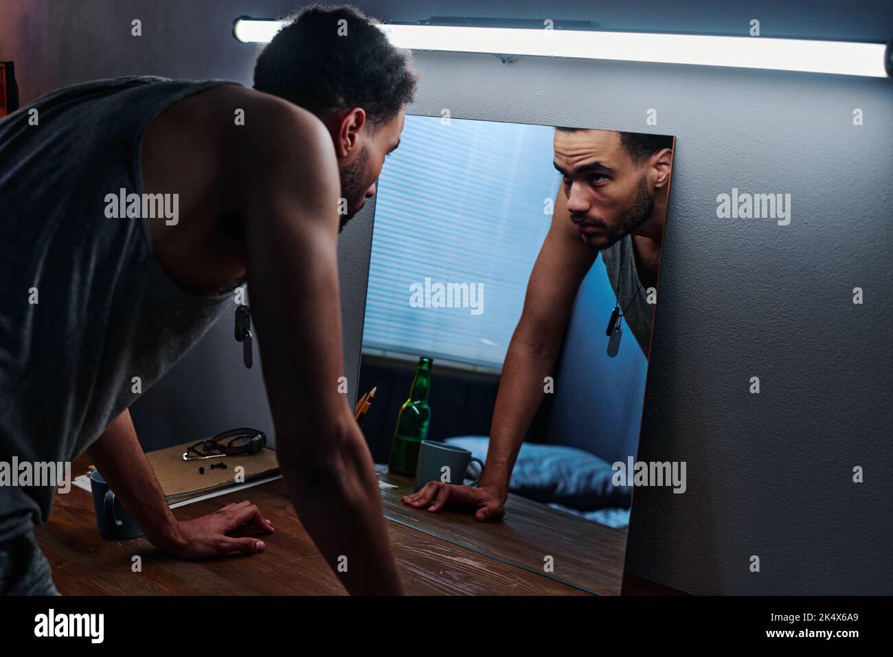 Young man with post traumatic disorder bending over table and looking ...
