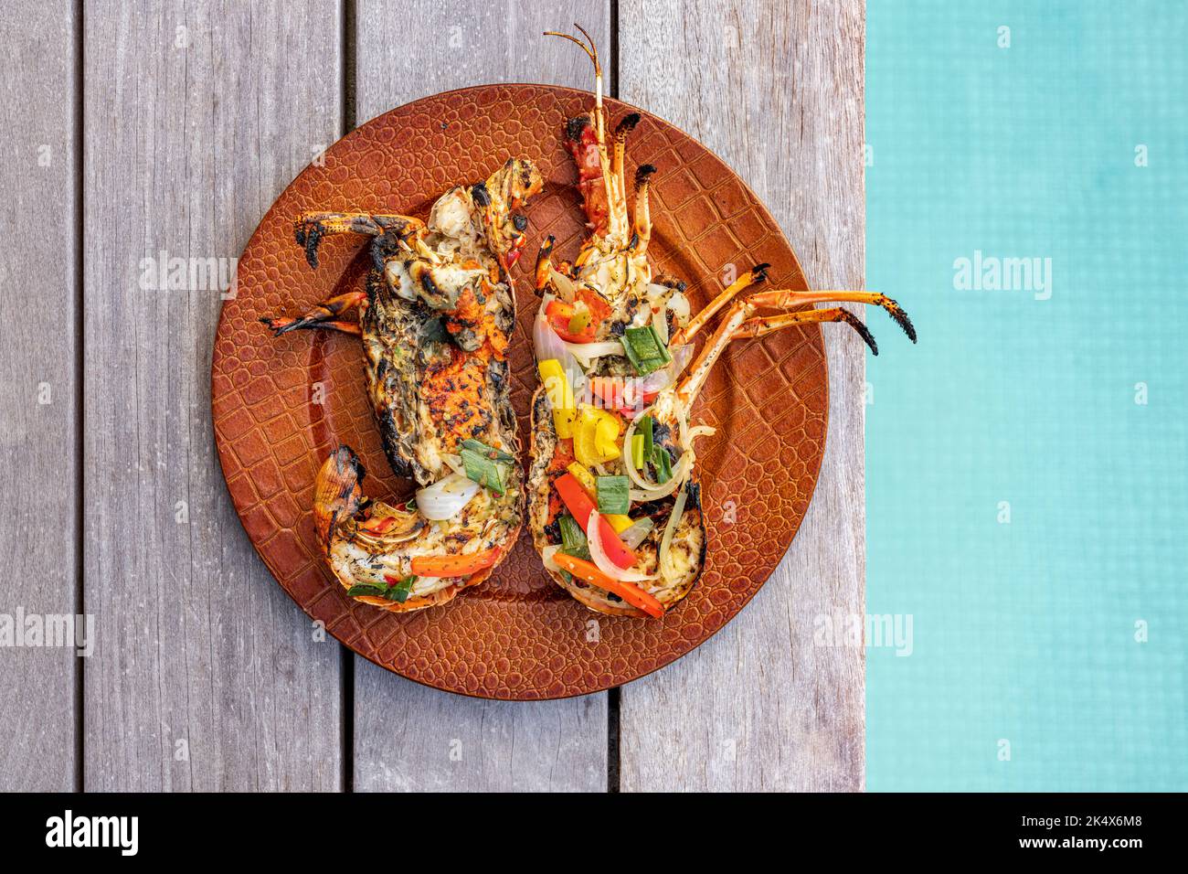 High angle view of grilled lobsters in a dish on edge of swimming pool ...