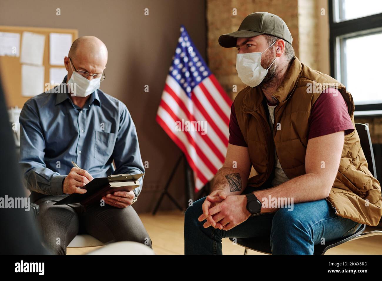 Mature counselor making notes while stressed man describing his ...