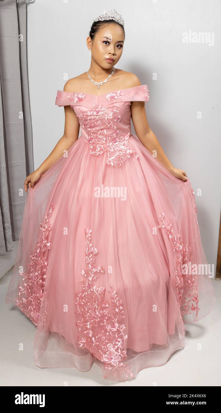 A vertical shot of a beautiful Filipino girl in a pink princess costume ...