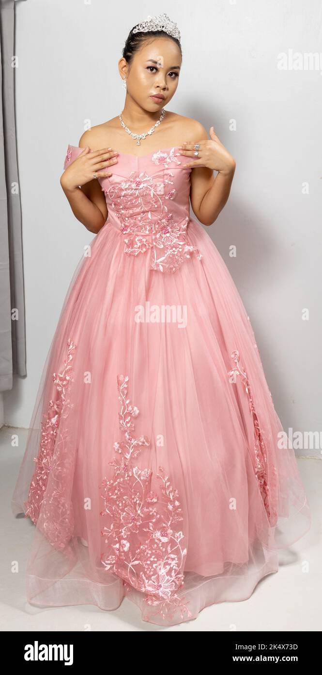 A vertical shot of a beautiful Filipino girl in a pink princess costume ...