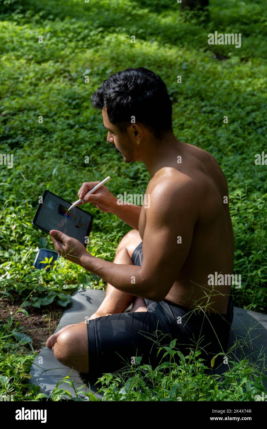 young man explaining drawing on his tablet, while teaching chakra, yoga ...
