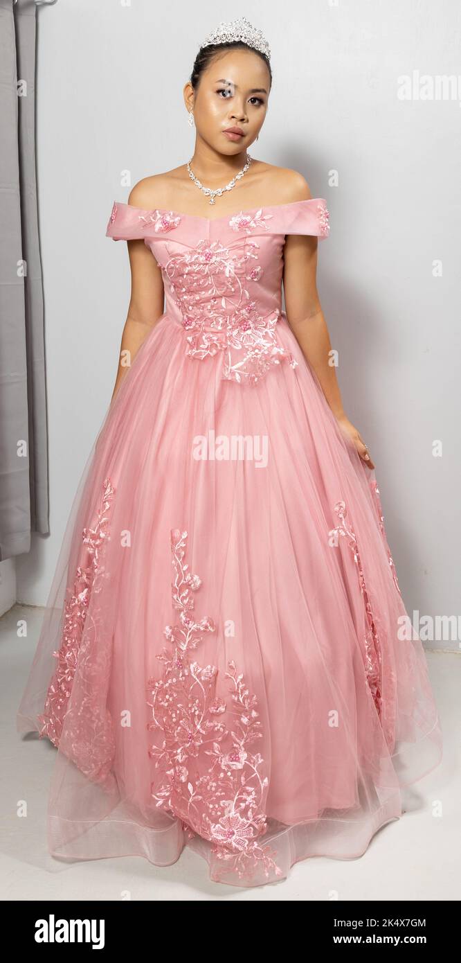 A vertical shot of a beautiful Filipino girl in a pink princess costume ...