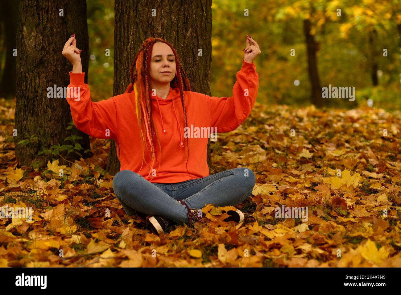 Young woman with dreadlocks meditating with closed eyes, sitting near ...