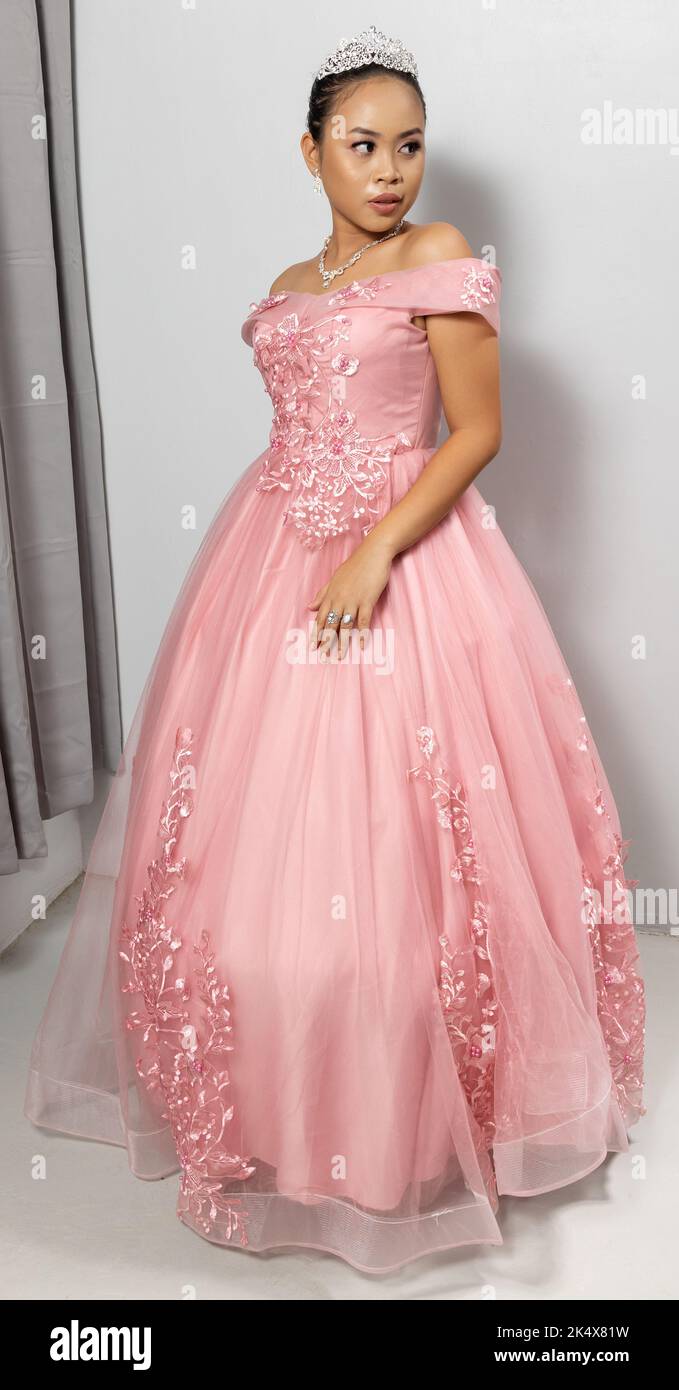 A vertical shot of a beautiful Filipino girl in a pink princess costume ...